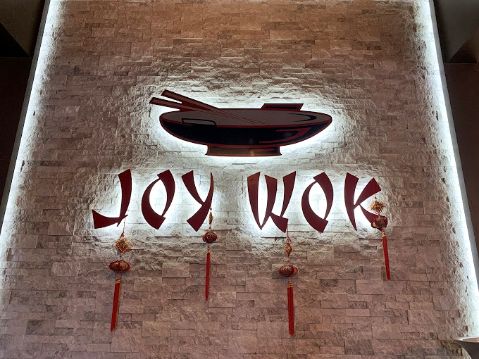 The illuminated Joy Wok sign serves as both restaurant branding and nightlight for those dreaming of dumplings after their visit.