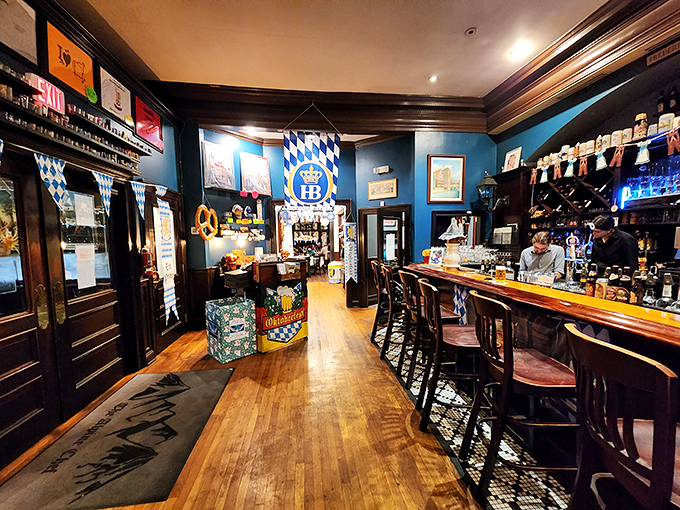 The bar area glows with Bavarian blue warmth, where beer steins stand at attention like soldiers guarding liquid gold.