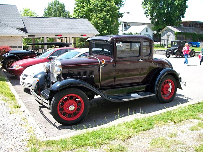 The gleaming black 1931 Ford with its distinctive red wheels demonstrates why these machines transcend transportation to become rolling art.
