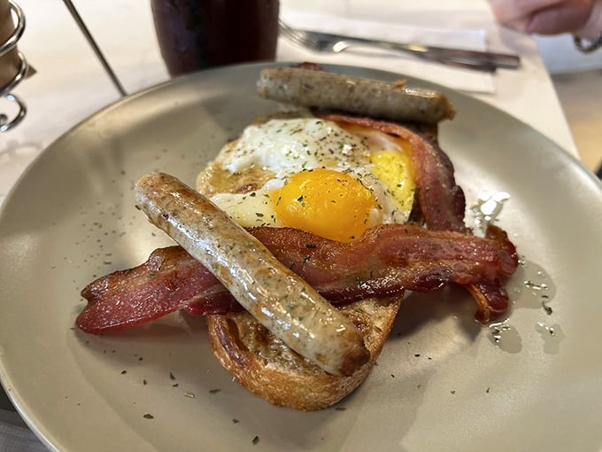 Breakfast simplicity perfected: golden toast, crispy bacon, perfectly cooked eggs, and sausage links that demand to be savored slowly.