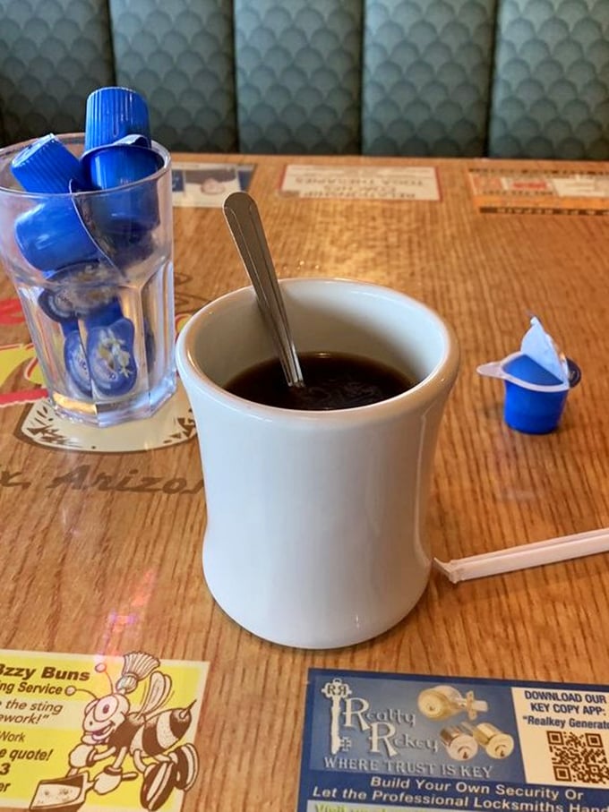 That classic white mug holds liquid motivation, served alongside those little creamer cups that never pour without making a statement.