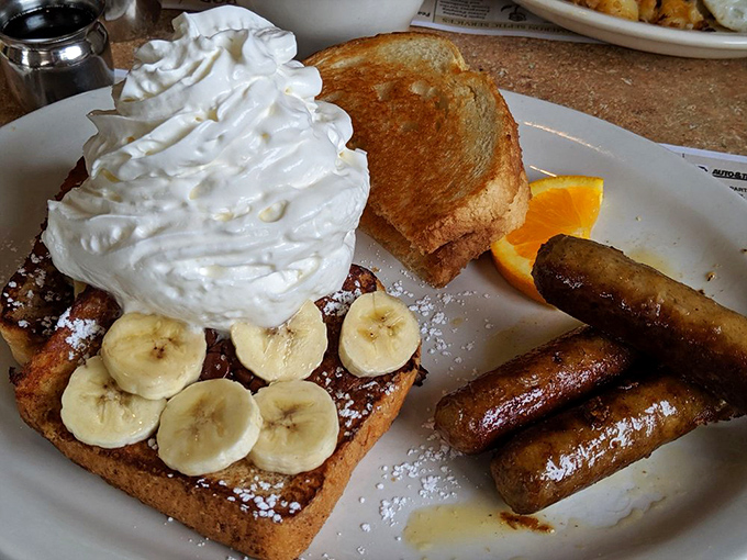 French toast that's dressed for success with whipped cream, bananas, and a side of sausage links playing the perfect supporting role.