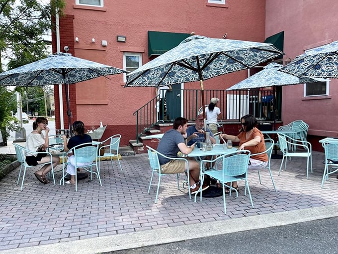 Outdoor seating that says "Yes, your breakfast can come with vitamin D and a gentle breeze" under patterned umbrellas.