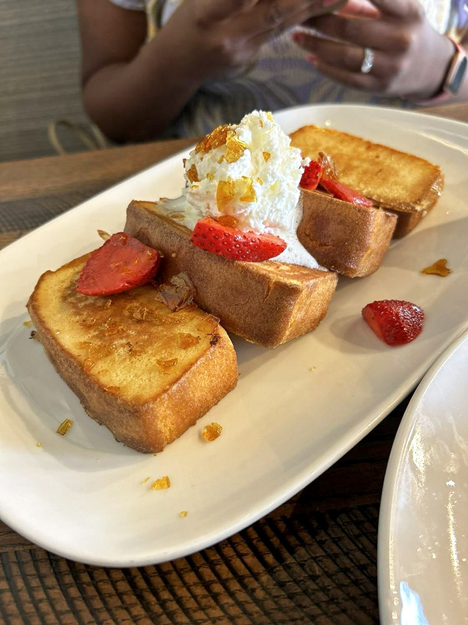 French toast transformed into dessert's breakfast cousin—golden slices topped with fresh strawberries and cream that make pancakes jealous.