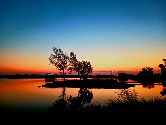 Sunset paints the water with impossible colors. Oklahoma skies showing off again, turning an ordinary evening into visual dessert.