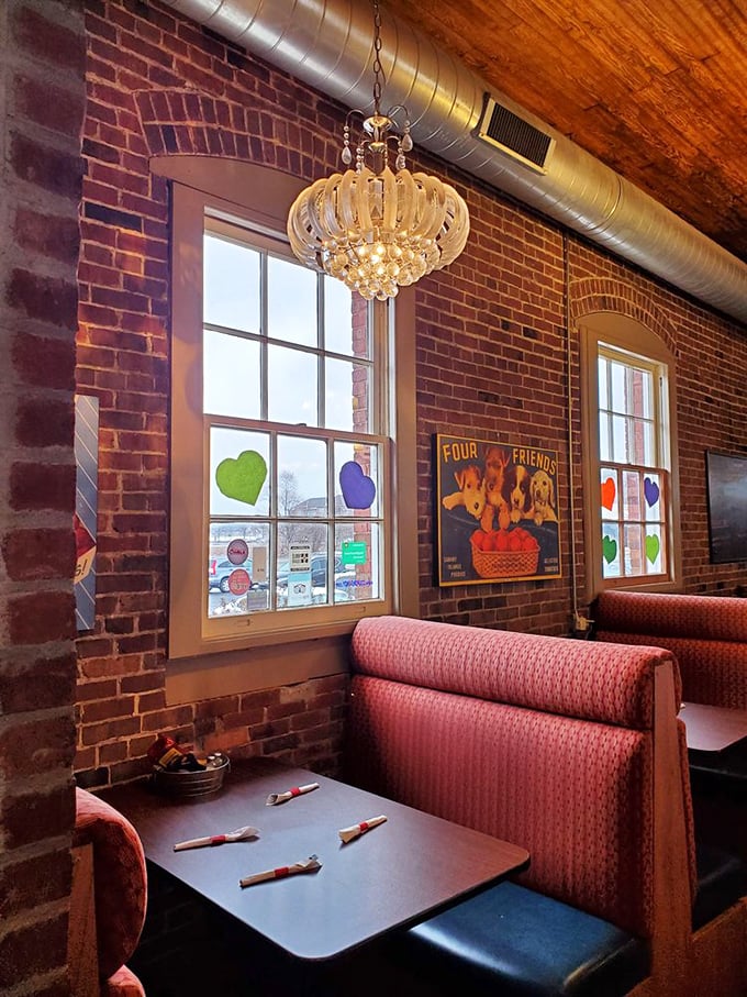 Booth seating that invites you to linger longer than planned. The elegant chandelier above rustic brick proves that opposites really do attract.