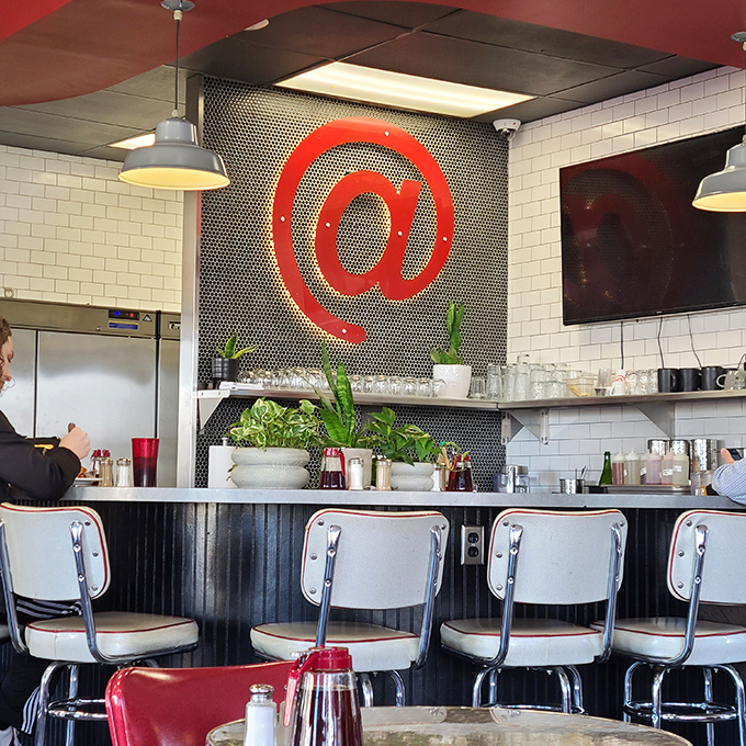 The counter seats offer front-row tickets to the culinary show, where the @ symbol presides over all like a modern diner deity.