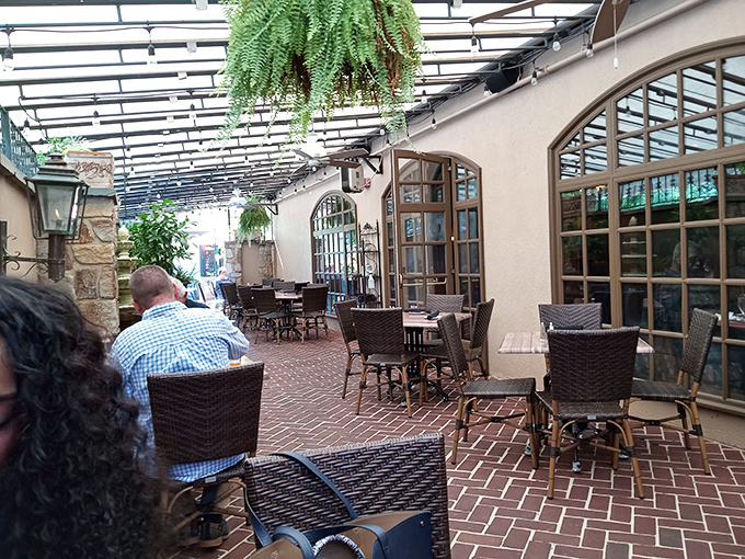 The outdoor dining area at Harry's offers a Mediterranean-inspired escape, where hanging ferns and brick pavers set a relaxed mood.