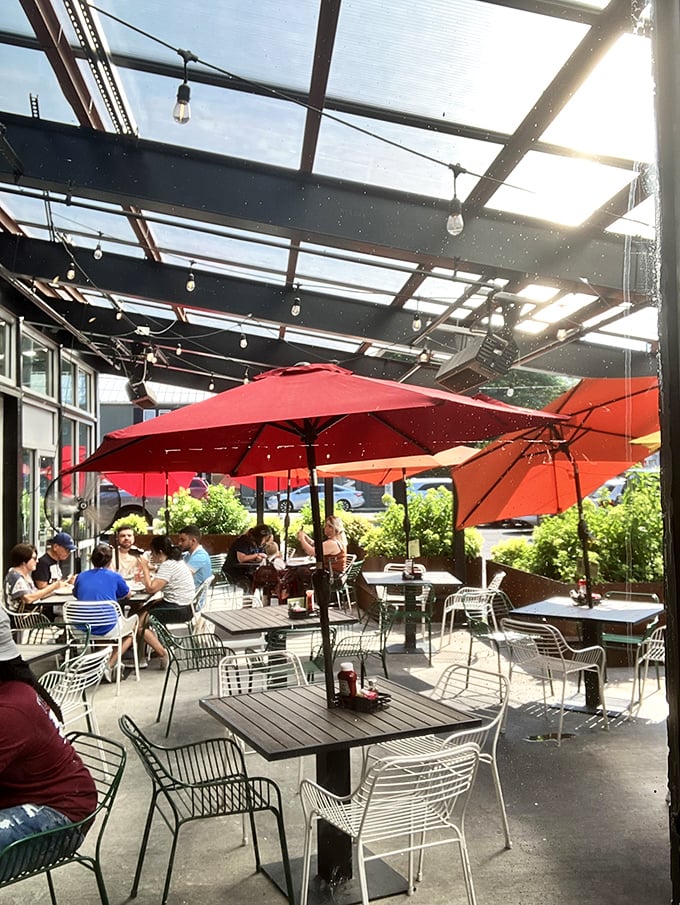 Red umbrellas create islands of shade where breakfast enthusiasts gather like morning worshippers at the altar of good food.
