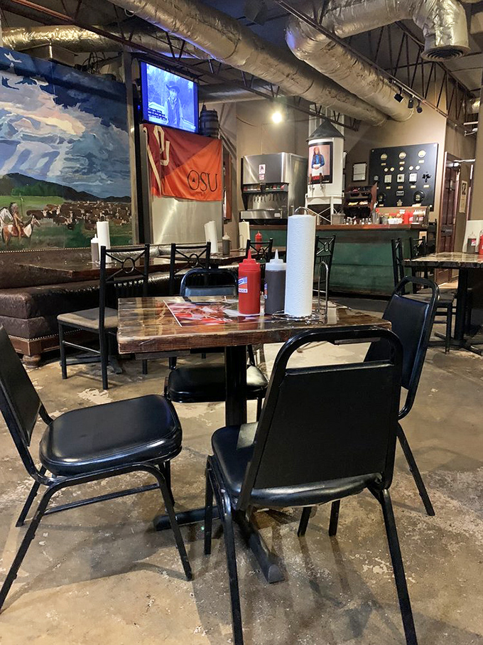 Inside, exposed ductwork meets Oklahoma pride. The OSU flag and cattle mural remind you this isn't just dinner&mdash;it's a cultural experience.