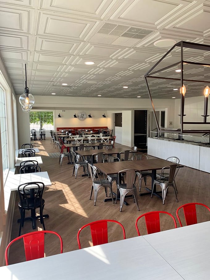 Sunlight streams across polished wood tables and those eye-catching red chairs, creating the perfect backdrop for the comfort food drama about to unfold on your plate.