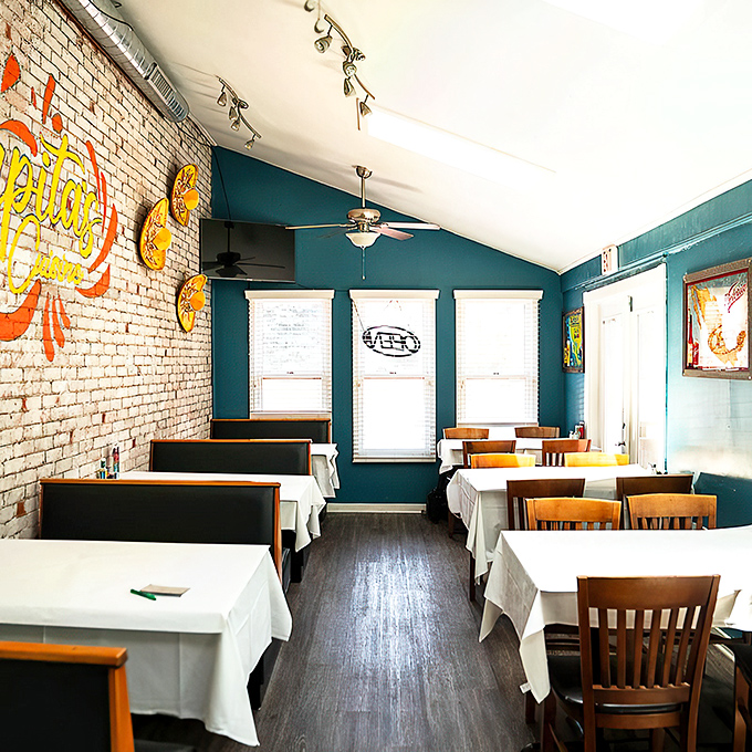 Exposed brick meets teal walls in this dining room that feels both upscale and homey. White tablecloths say "special occasion" while the vibe whispers "come as you are."