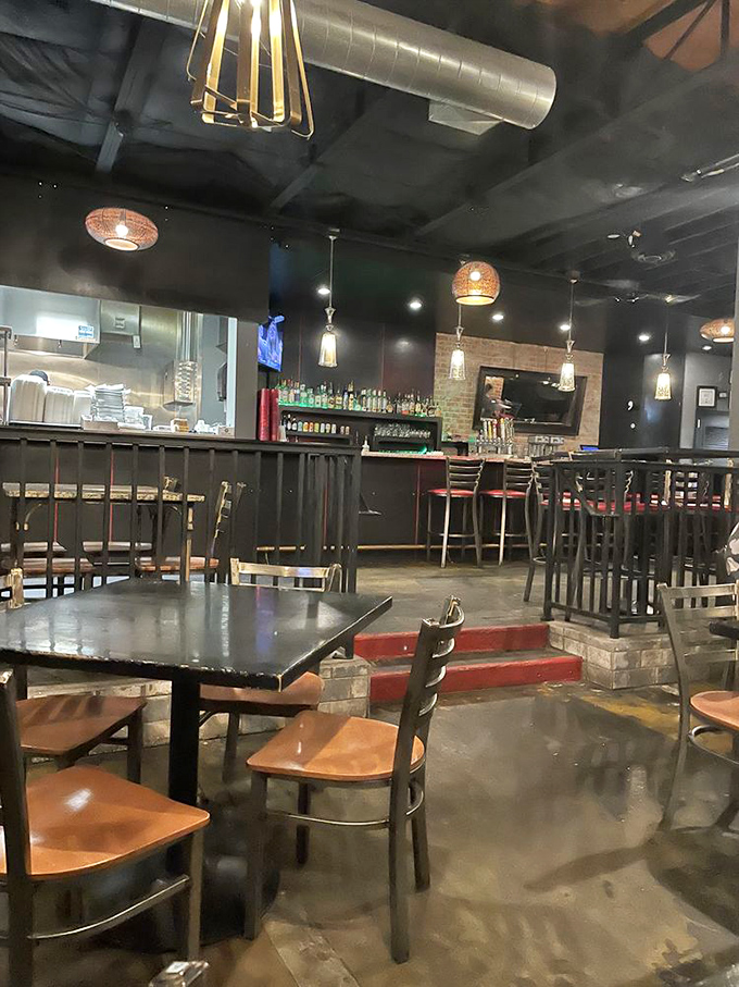 The industrial-chic interior balances dive bar cool with burger joint comfort—dark walls, pendant lighting, and an atmosphere that whispers, "Your diet ends here."