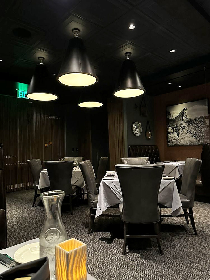 Elegant black pendant lights cast a warm glow over white tablecloths, creating an atmosphere where Oklahoma's ranching heritage meets sophisticated dining.