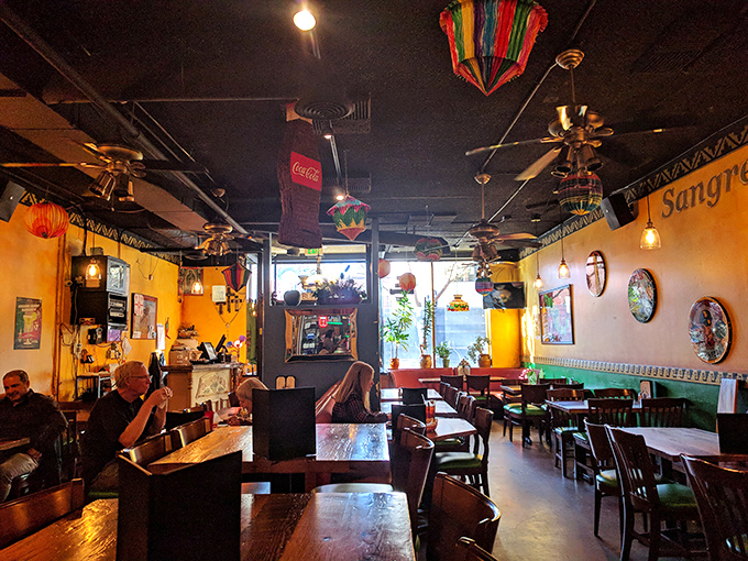 Warm golden walls, colorful decorations, and ceiling fans create an atmosphere that whispers "authenticity" louder than any neon sign ever could.