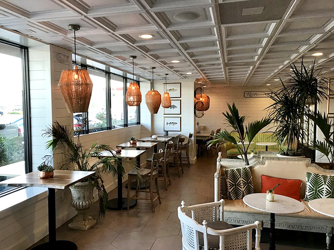 Coastal chic defined: wicker pendant lights, tropical plants, and bright white shiplap create that "I could live here" feeling we all secretly crave in restaurants.
