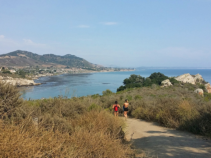 The path less traveled leads to treasures untold. Two hikers descend toward coastal magic that no Instagram filter could possibly improve.