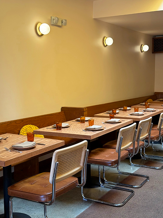 Minimalist wooden tables and cane-backed chairs create an atmosphere that whispers, "We're serious about food, not pretension." Comfort meets sophistication.