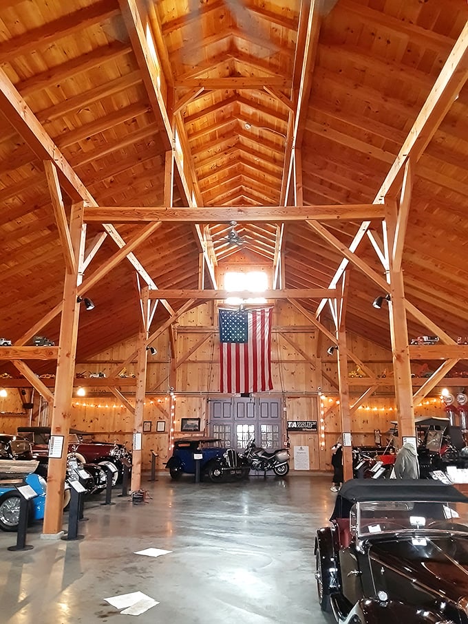 Soaring wooden beams frame this cathedral to combustion engines, where an American flag hangs proudly above a collection of mechanical marvels.