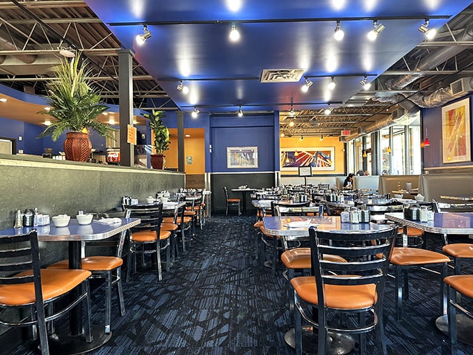 Blue walls and orange chairs create the perfect canvas for breakfast drama. The stage is set for hash brown heroics and pancake performances.