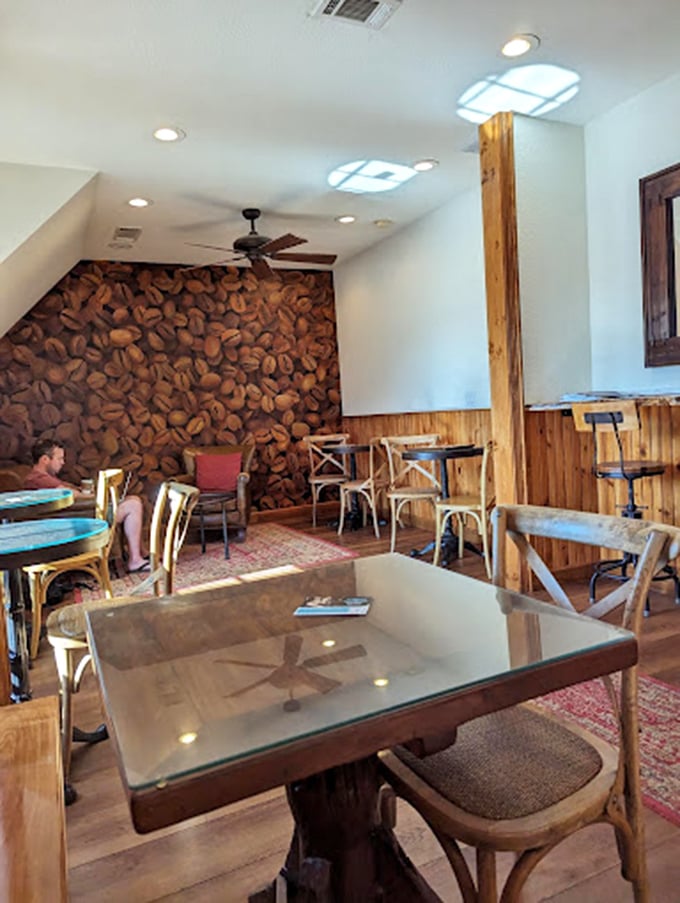 Coffee bean wallpaper that doesn't just decorate&mdash;it announces a mission statement. This cozy corner with wooden accents and glass-topped tables is where caffeine dreams come true.