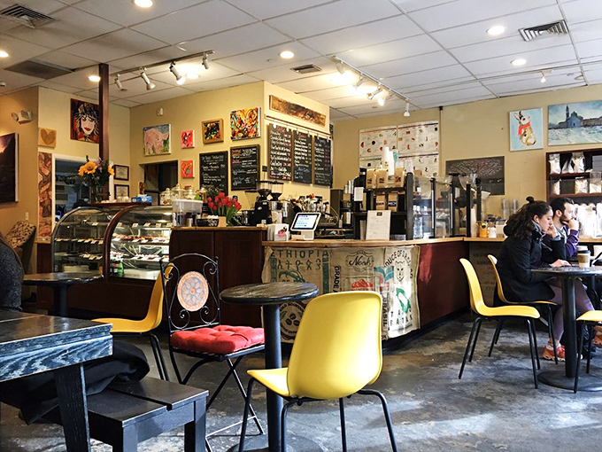 Not just a coffee shop, but a community living room where yellow chairs pop against the warm wood tones and local art transforms ordinary walls into conversation starters.