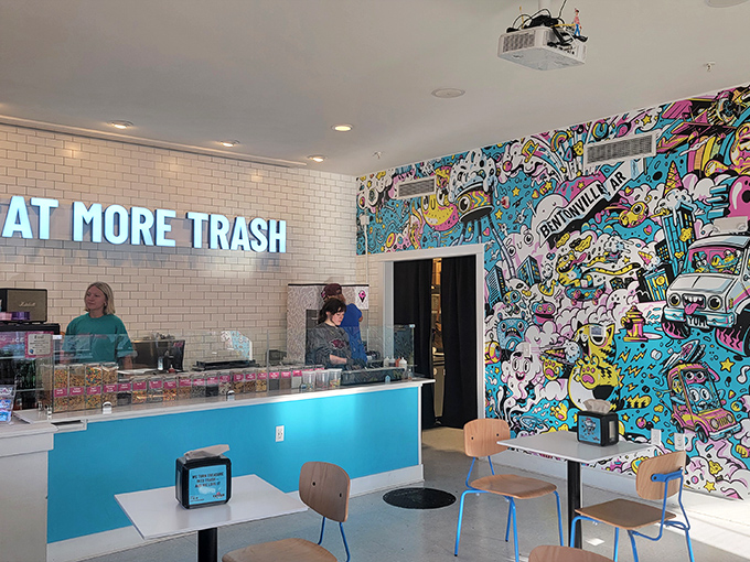 The "EAT MORE TRASH" neon sign isn't just a suggestion&mdash;it's practically a dare, glowing against pristine subway tiles and that eye-popping mural of pop culture chaos.