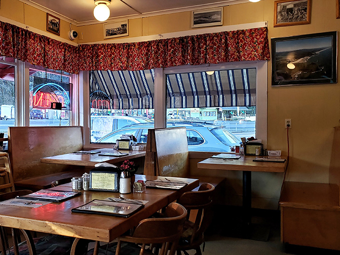 Cozy wooden tables, floral curtains, and coastal photographs create that perfect small-town diner atmosphere where conversations flow as freely as the coffee. 