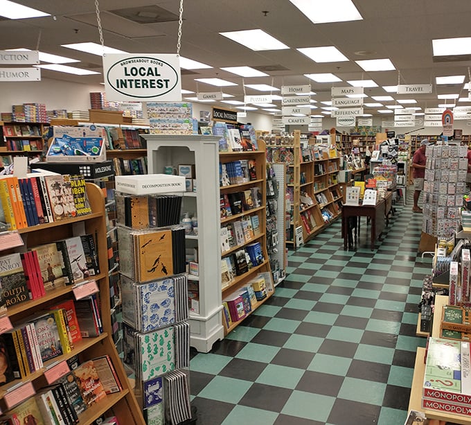 Wooden shelves create literary canyons beneath helpful hanging signs, a bibliophile's dream map to navigate this paper paradise.