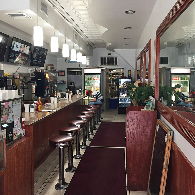 Classic counter seating invites you to linger over coffee and conversation, where vintage red stools and no-nonsense lighting tell you you're in a place that prioritizes substance over style.