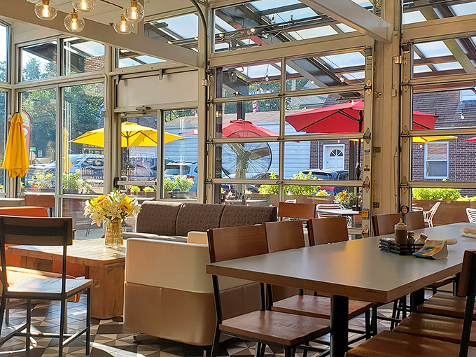 Sunshine floods through garage-style doors, turning ordinary breakfast into a light-drenched affair. Even the coffee looks happier here.