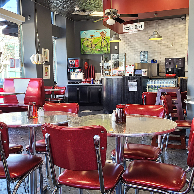 Retro meets modern with chrome-trimmed tables, vibrant red vinyl chairs, and warm lighting creating that "everybody knows your name" atmosphere.