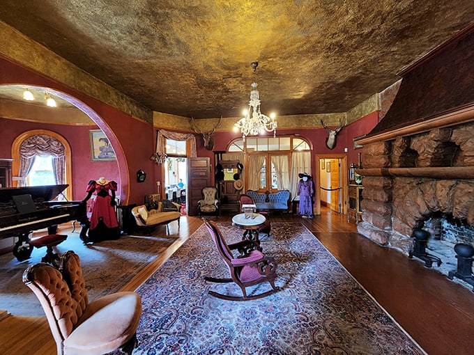 The grand parlor welcomes visitors with rich crimson walls, a golden ceiling, and furnishings that whisper tales of Victorian sophistication.