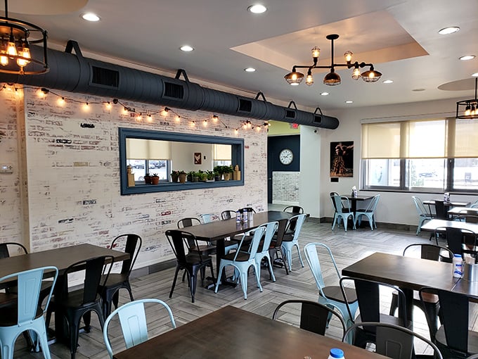 Industrial-chic meets Mediterranean warmth inside, where exposed brick walls, string lights, and those eye-catching blue chairs create the perfect backdrop for culinary adventures.