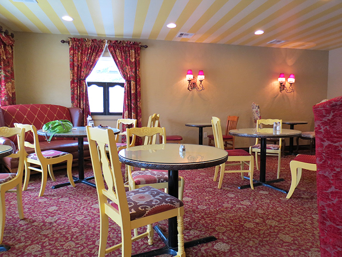Step into a storybook dining room where yellow striped ceilings, pink wall sconces, and floral patterns create the perfect backdrop for sweet indulgences.