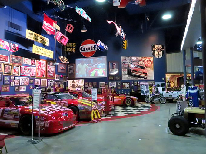 Inside, history hangs from the rafters as vintage signs and memorabilia create a cathedral of combustion where race cars rest like sleeping dragons waiting for their next run.