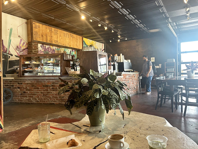Inside, exposed brick meets lush greenery, creating that rare space where industrial chic and actual comfort manage to coexist peacefully.