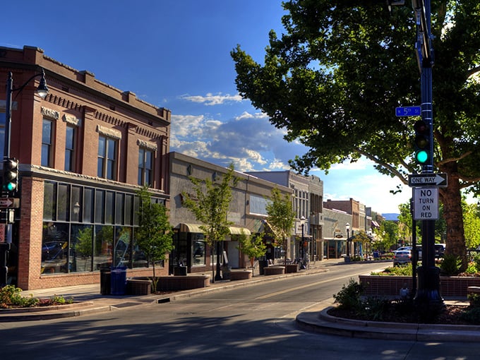 Sunlight warms the historic brick buildings of Grand Junction as you stroll down this charming, tree-lined street on a quiet afternoon.