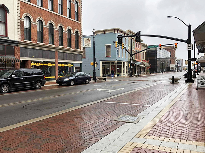 Rain-slicked streets reflect the architectural diversity of downtown Muncie, where brick-paved sidewalks invite leisurely exploration rather than hurried commutes.