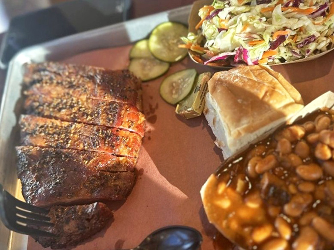Behold the perfect BBQ trifecta: bark-crusted ribs with that pink smoke ring, homemade baked beans, and slaw that knows its supporting role.