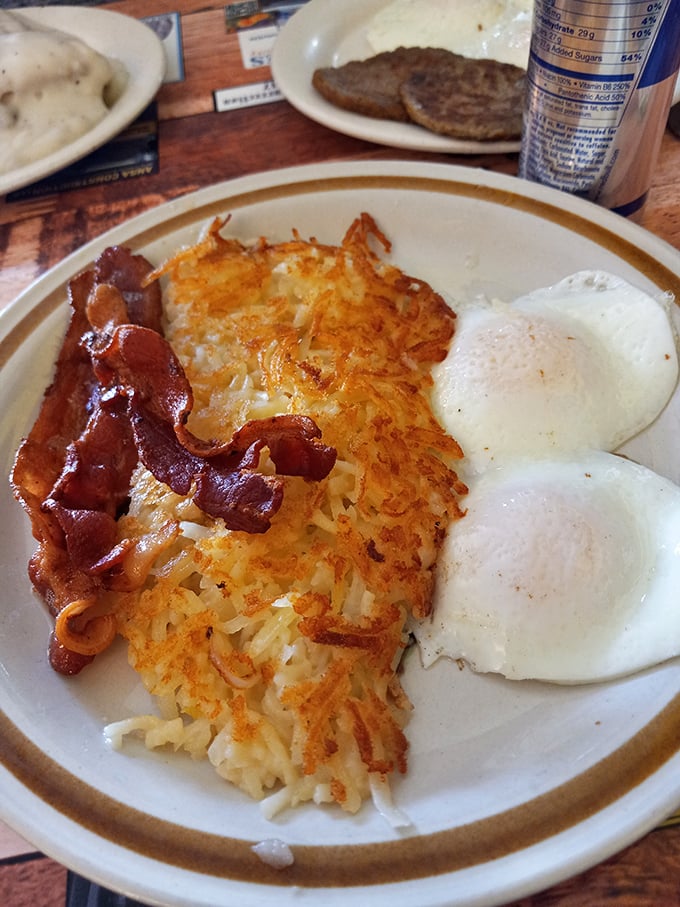 The holy trinity of breakfast perfection: crispy bacon, eggs with just-right yolks, and those legendary hash browns that justify the journey.