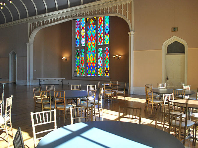 Sunlight streams through stained glass windows, transforming this banquet hall into a kaleidoscope of colors that would make any wedding photographer swoon.