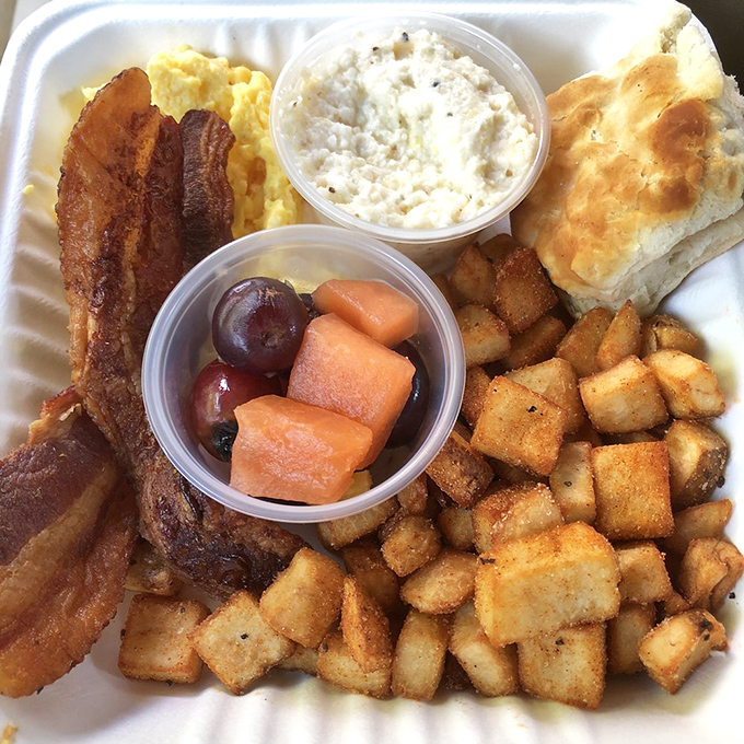 Breakfast nirvana achieved: crispy home fries, perfectly scrambled eggs, fresh fruit, and a biscuit that would make your Southern grandmother weep with joy.