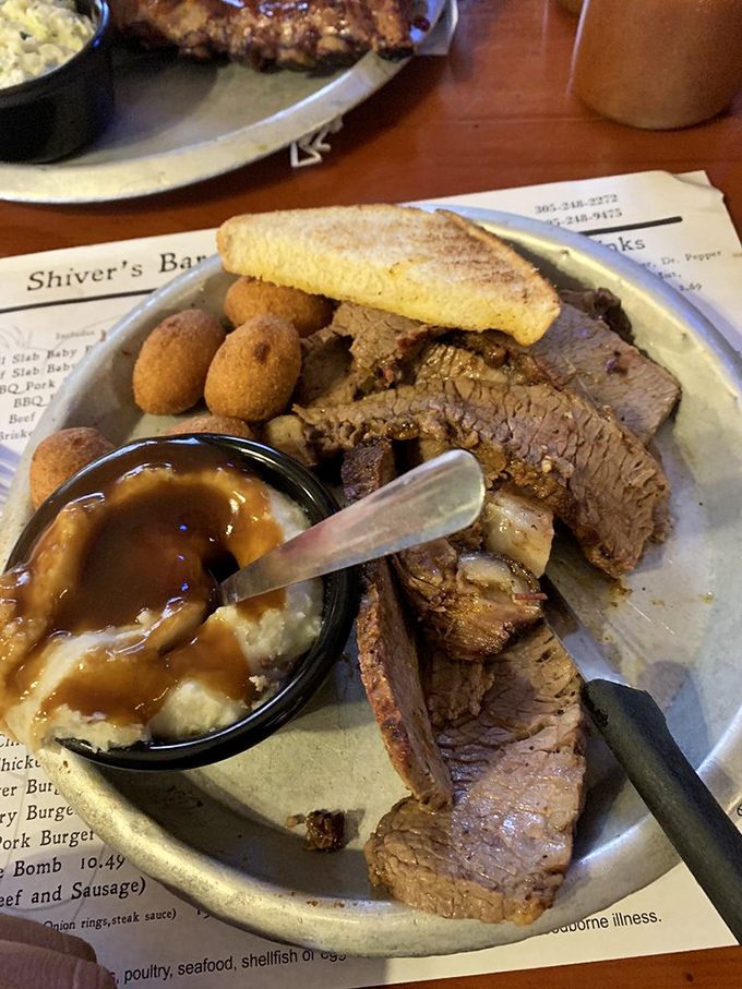 Brisket so tender it practically surrenders to your fork, served with hush puppies and mashed potatoes swimming in gravy. Comfort food nirvana achieved.