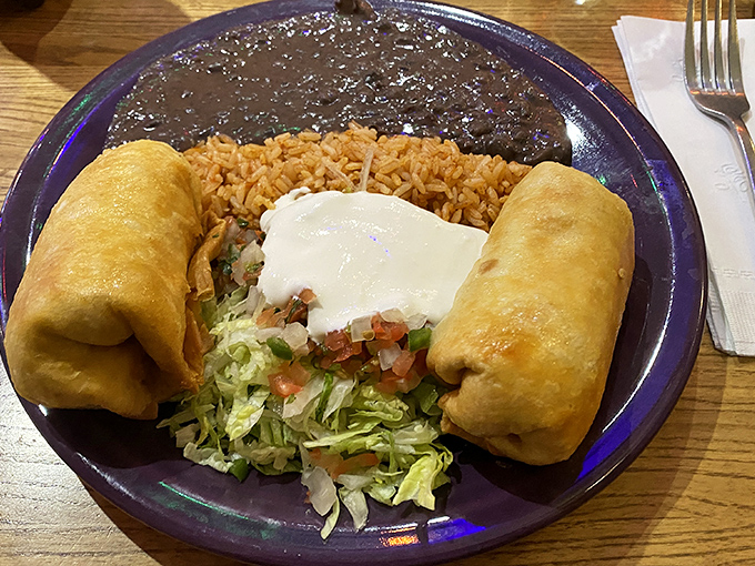 Golden-fried perfection meets savory filling in this chimichanga masterpiece, flanked by the classic trio of Mexican rice, beans, and fresh garnishes.