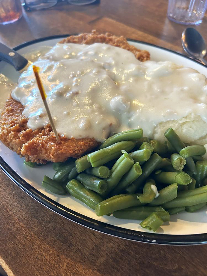 Behold the star attraction: golden-crusted chicken fried steak swimming in peppery gravy with green beans standing by as the token vegetable witness.