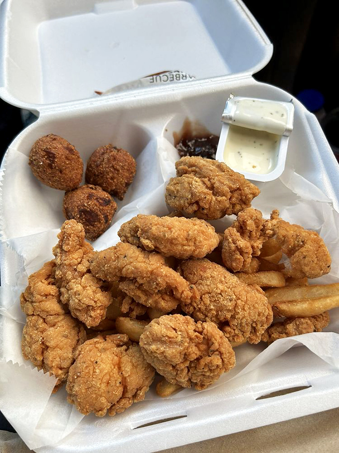 Golden-fried chicken tenders sharing space with those legendary hush puppies&mdash;proof that land and sea can coexist deliciously on one plate.