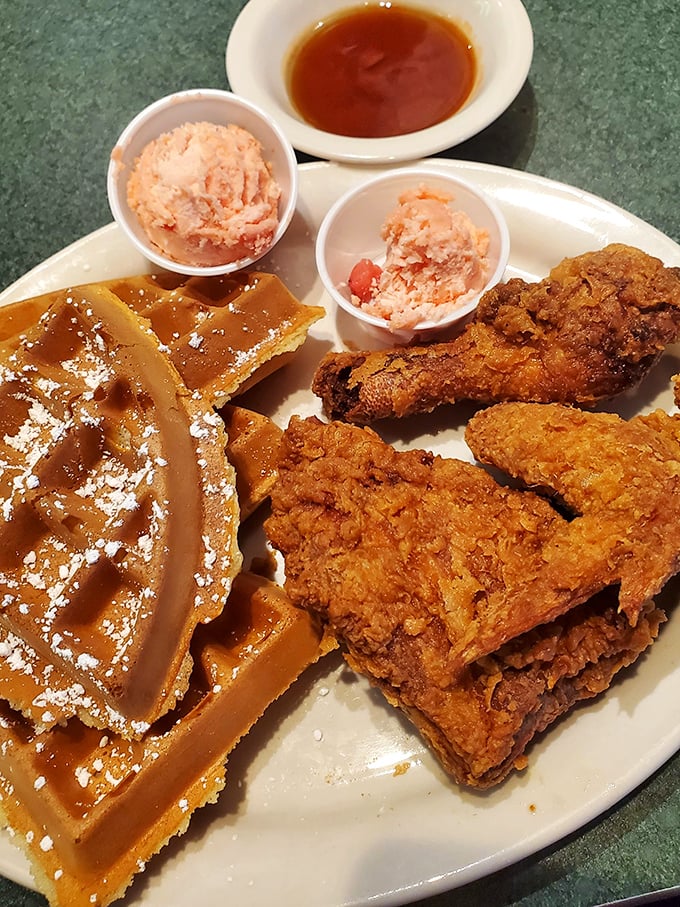 Behold the star attraction: golden-fried chicken meets Belgian waffle perfection. That strawberry butter is the supporting actor who steals the show.