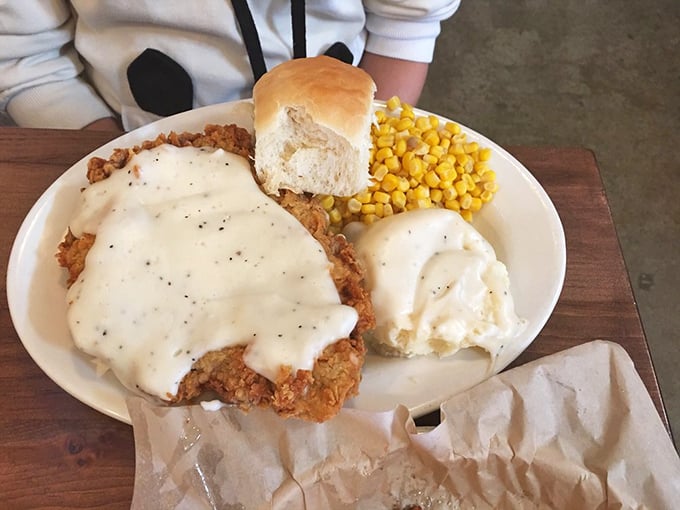 The star of the show in all its glory: chicken fried steak smothered in pepper-flecked gravy, with a side of sweet corn and a roll that's begging to mop up every last drop.
