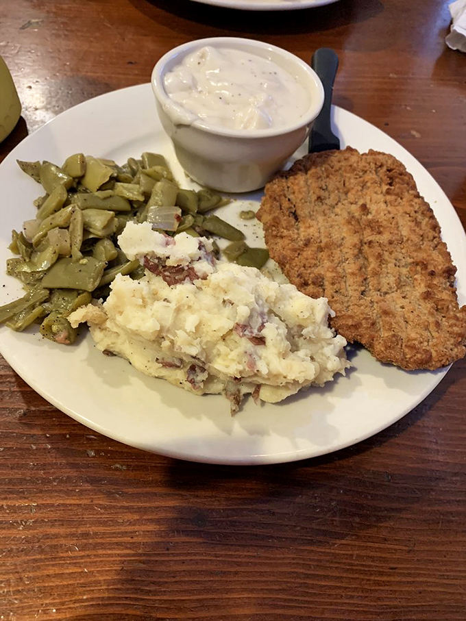 The star of the show arrives: golden-brown country fried steak with creamy gravy, mashed potatoes that clearly never saw a box, and green beans cooked to perfection.